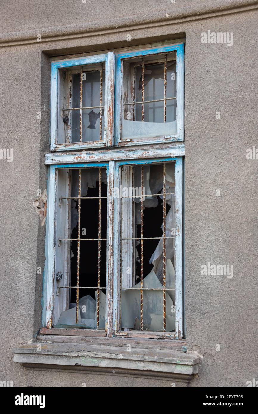 Old window with worn wooden shutters and broken glass on exterior wall ...