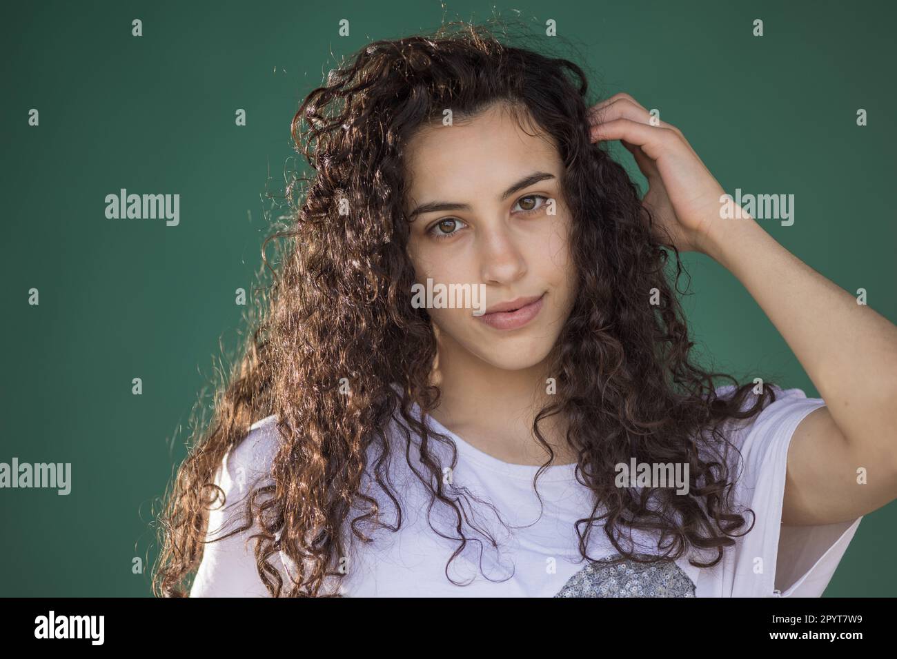 Portrait of pretty teenage girl with curly hair isolated against green ...