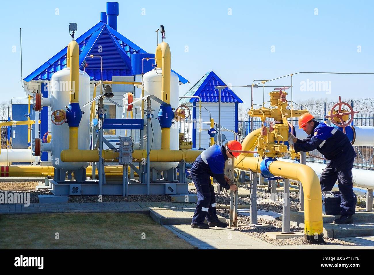 Two engineers in hard hats carry out maintenance work at gas ...