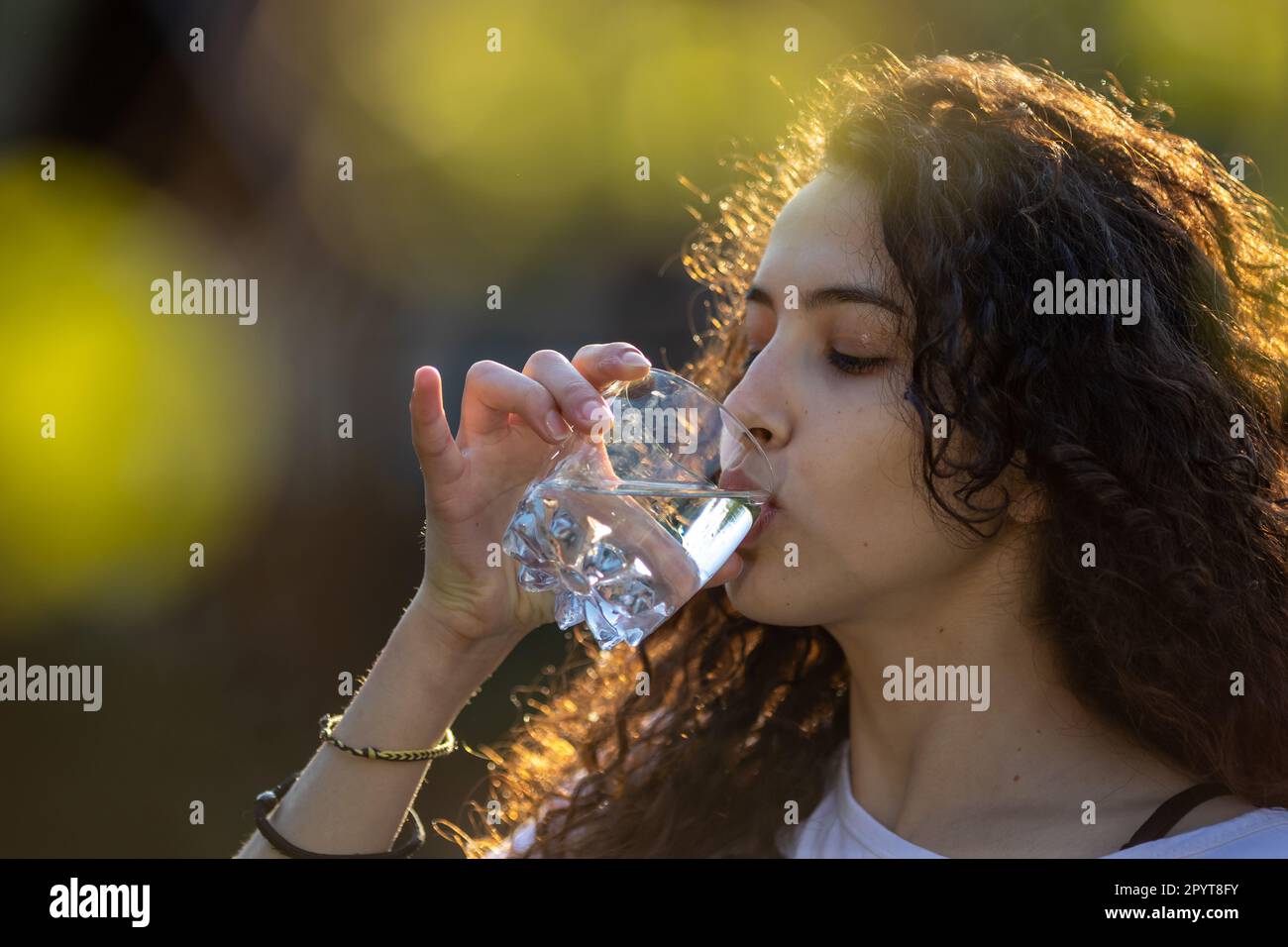Pretty young woman drinking water from glass in park Stock Photo - Alamy