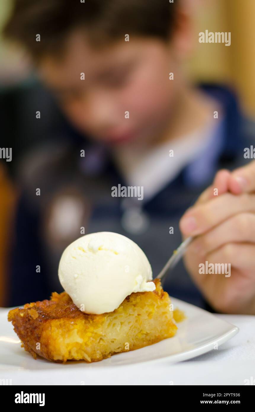 Kid eating traditional greek sweet with ice cream above at the ...