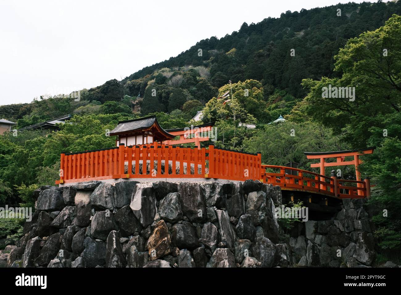 A vibrant red railing of a shrine on a slope of a green mountain in ...