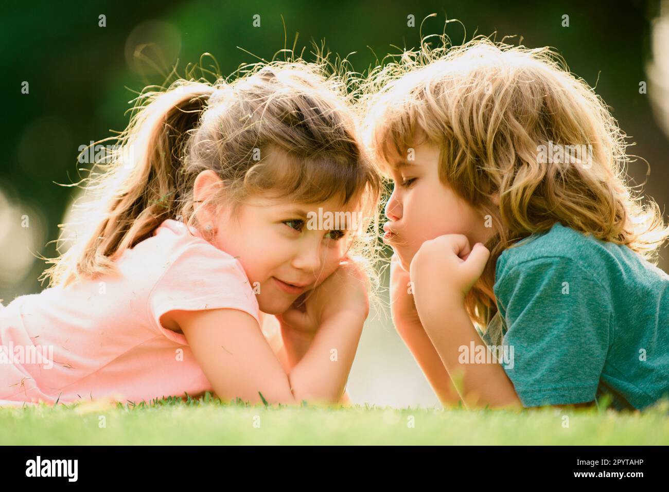 Two little children hug and kiss each other in summer garden. Kids ...