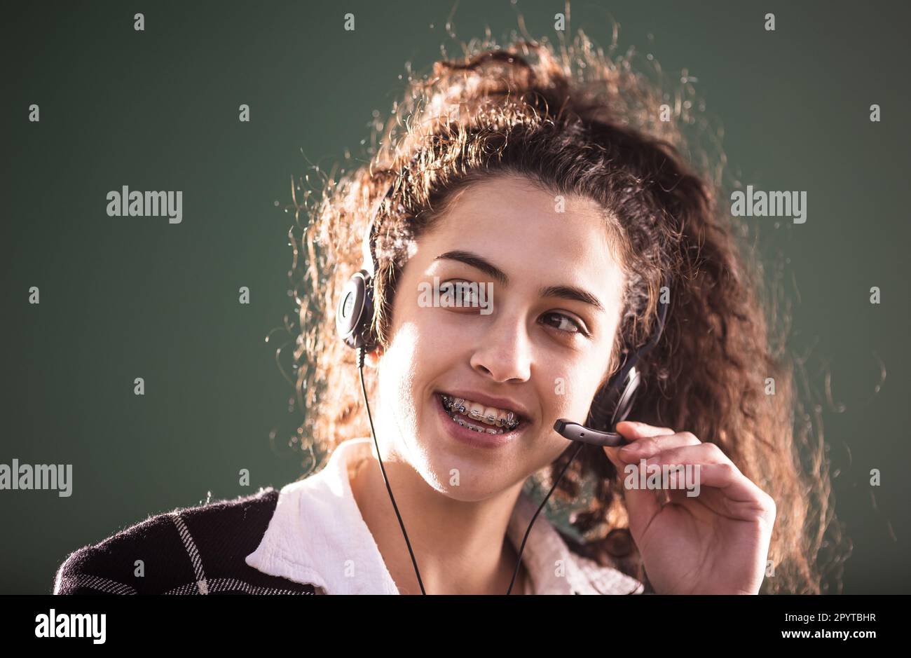 Pretty young woman with headphones and microphone smiling and working ...