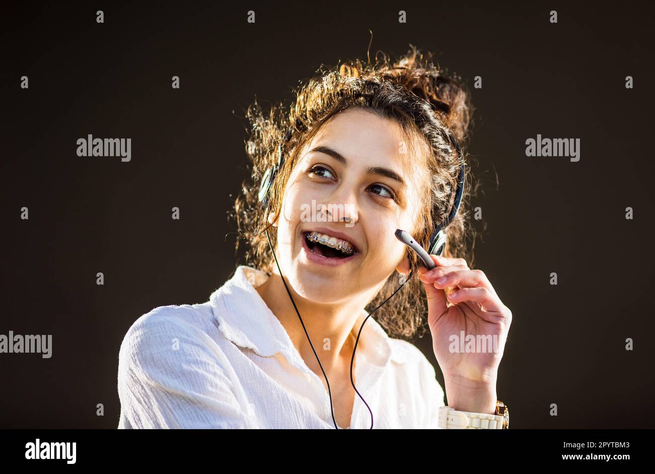 Pretty young woman with headphones and microphone smiling and working ...