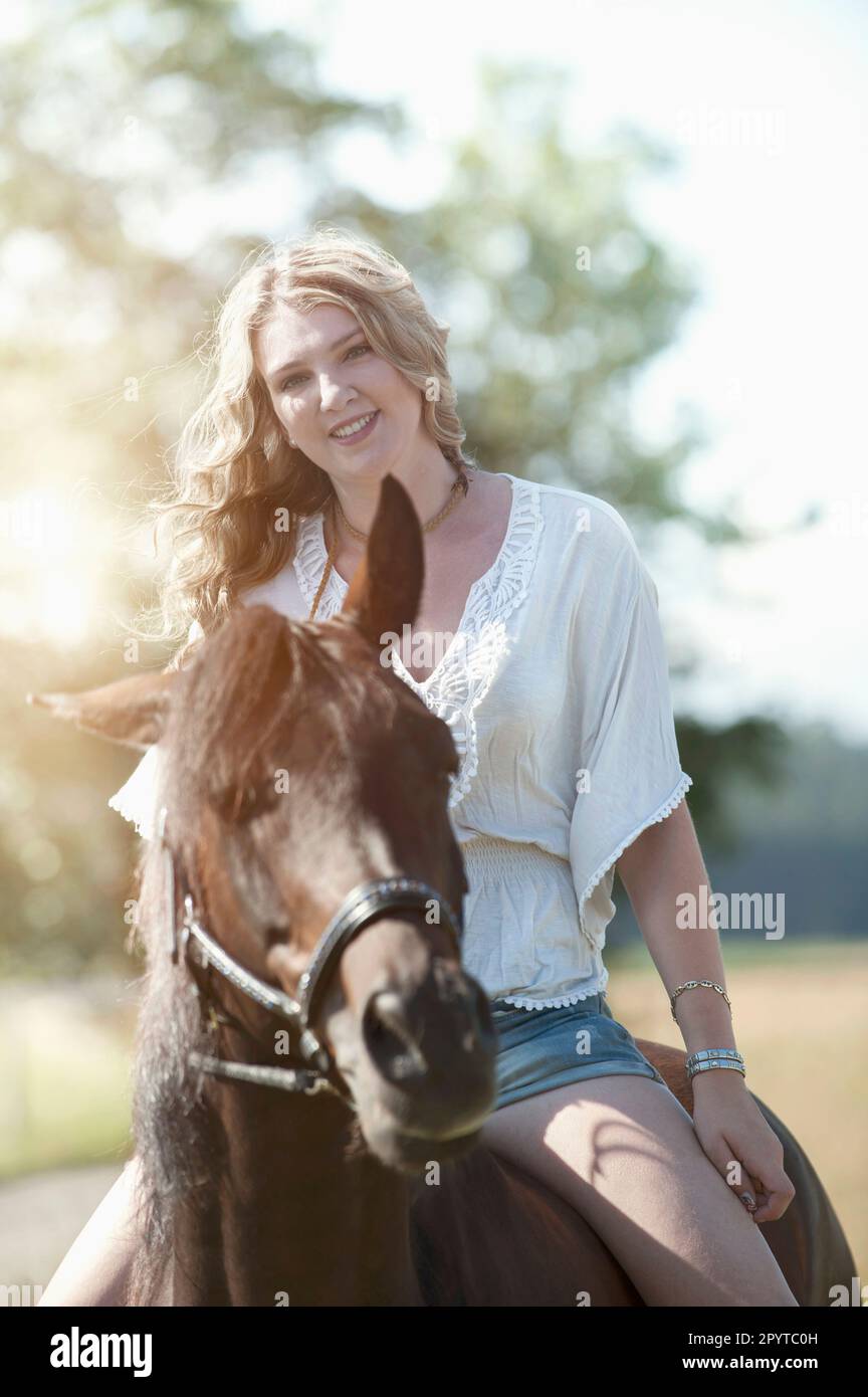 Portrait of a young woman riding a horse in farm and smiling, Bavaria ...