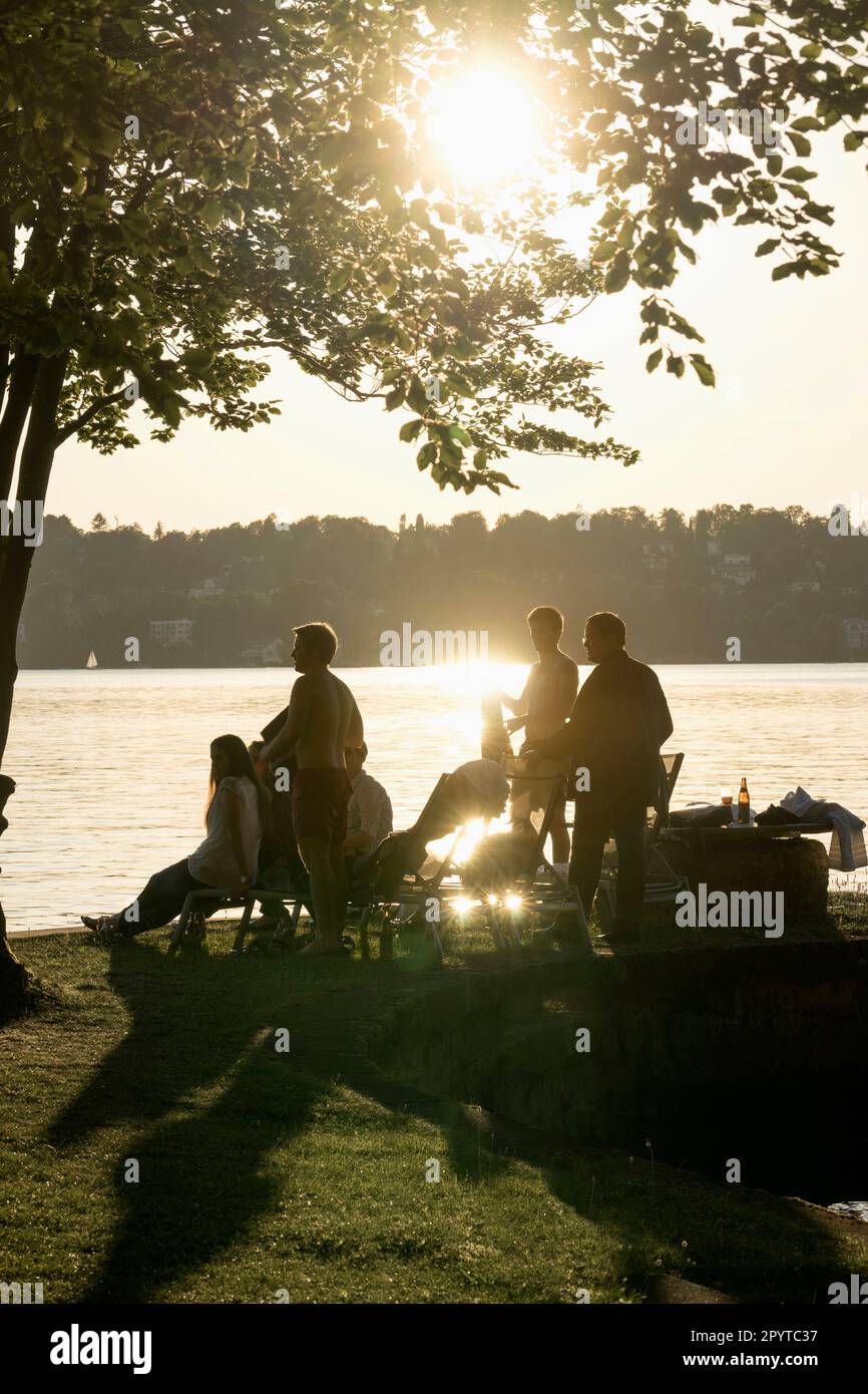 Group of young friends partying at lakeside during sunset, Bavaria ...
