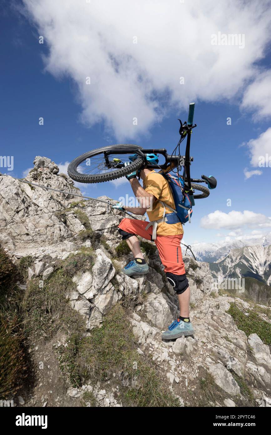 Mountain biker carries his bike on shoulder and walking uphill, Tirol ...