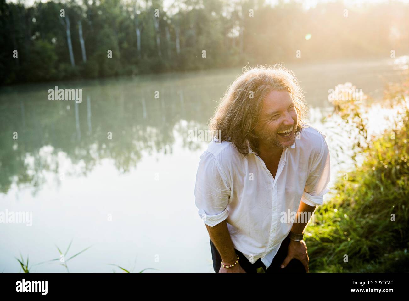 Cheerful man in long hair laughing by river, Bavaria, Germany Stock ...