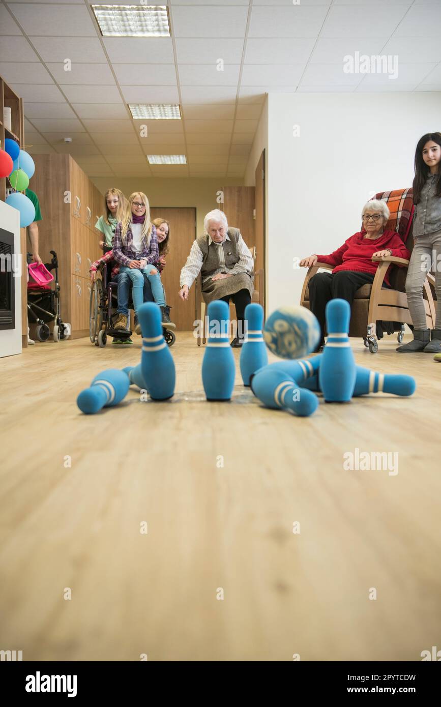 Girls playing bowling with senior women in rest home Stock Photo - Alamy