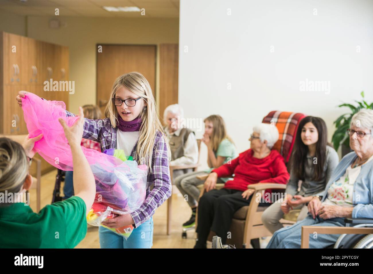 Girls pass out cloth to seniors for exercise in rest home Stock Photo ...