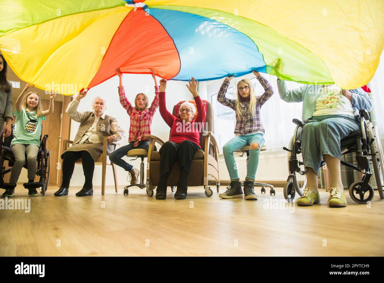 Girls and senior women doing gentle sports exercise with parachute in ...