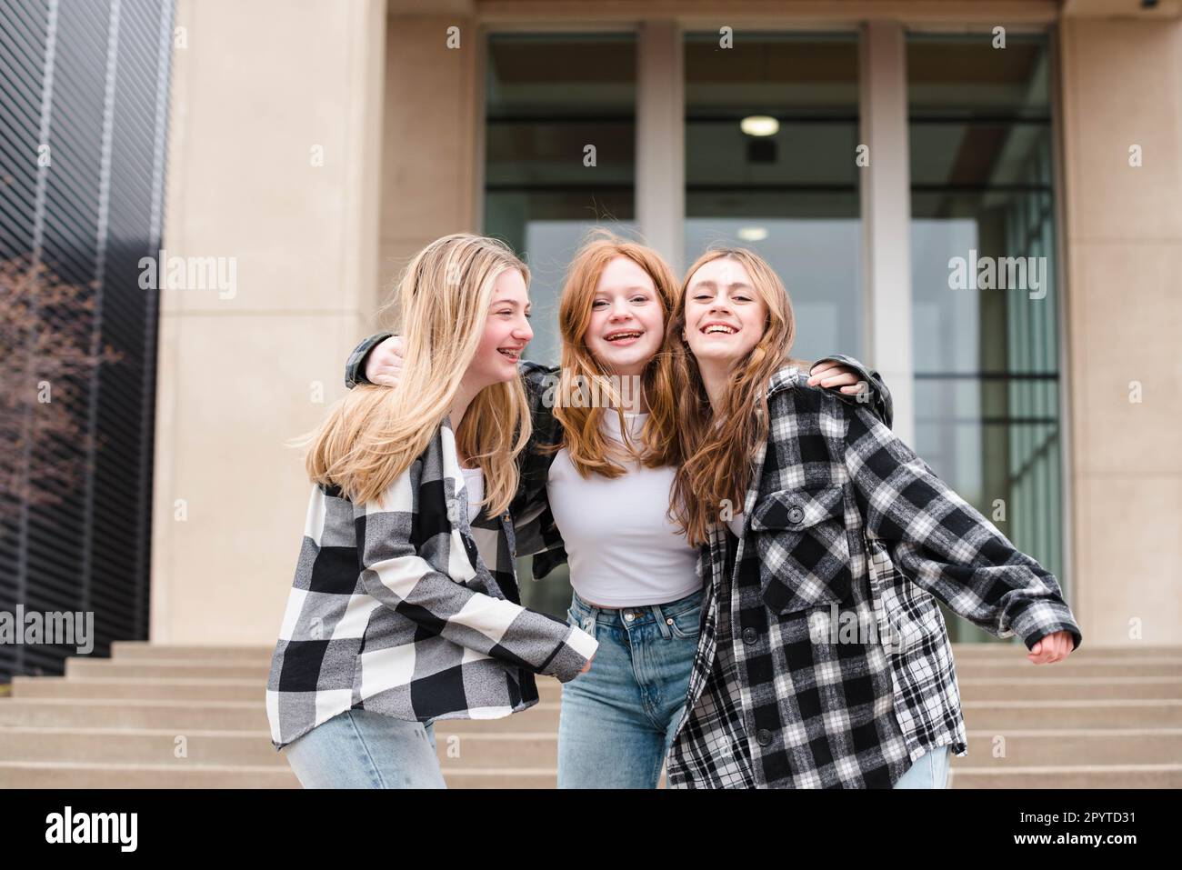 Three laughing teen girls hugging outdoors on steps Stock Photo - Alamy