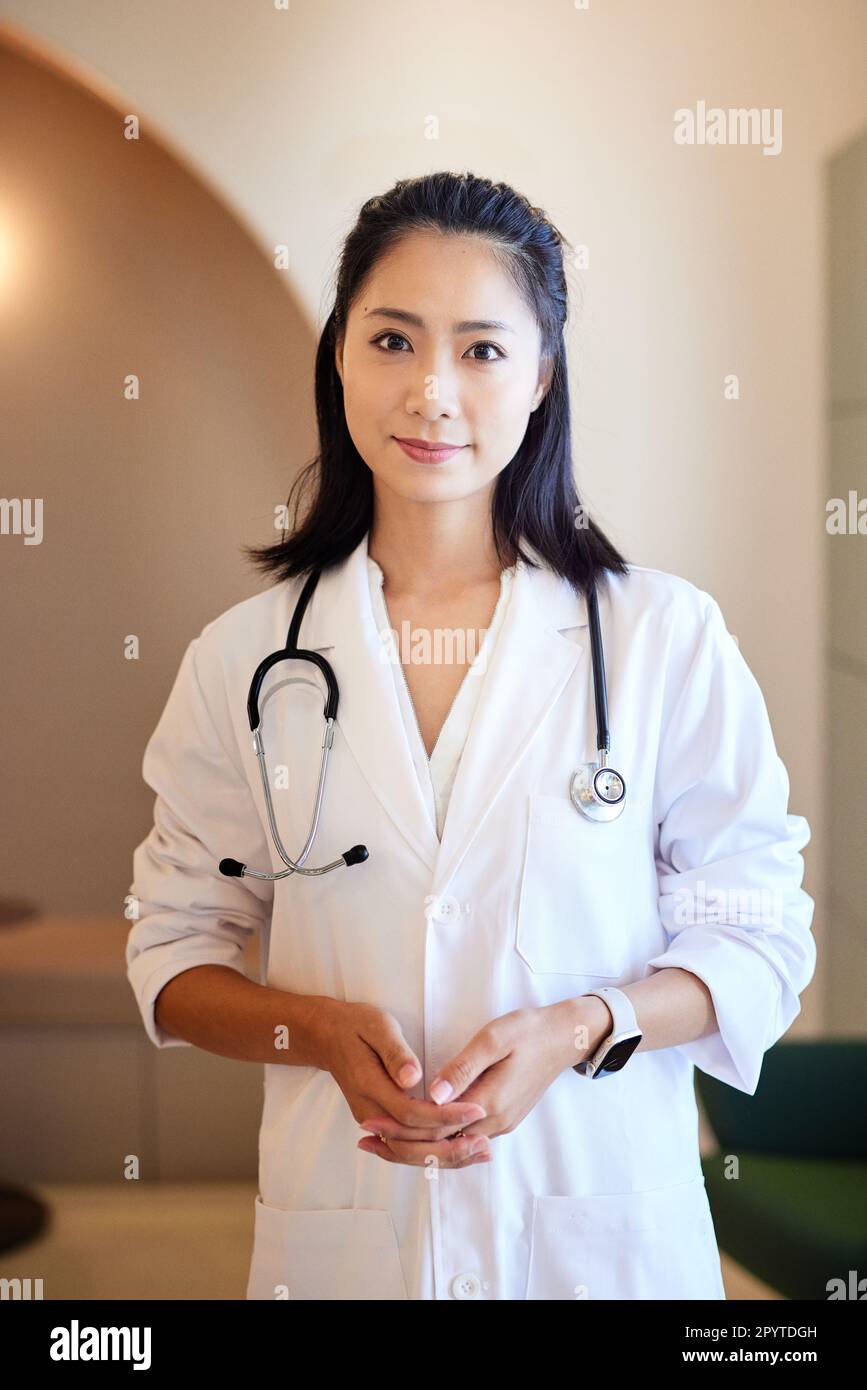 Portrait of female doctor wearing lab coat while standing in clinic Stock Photo - Alamy