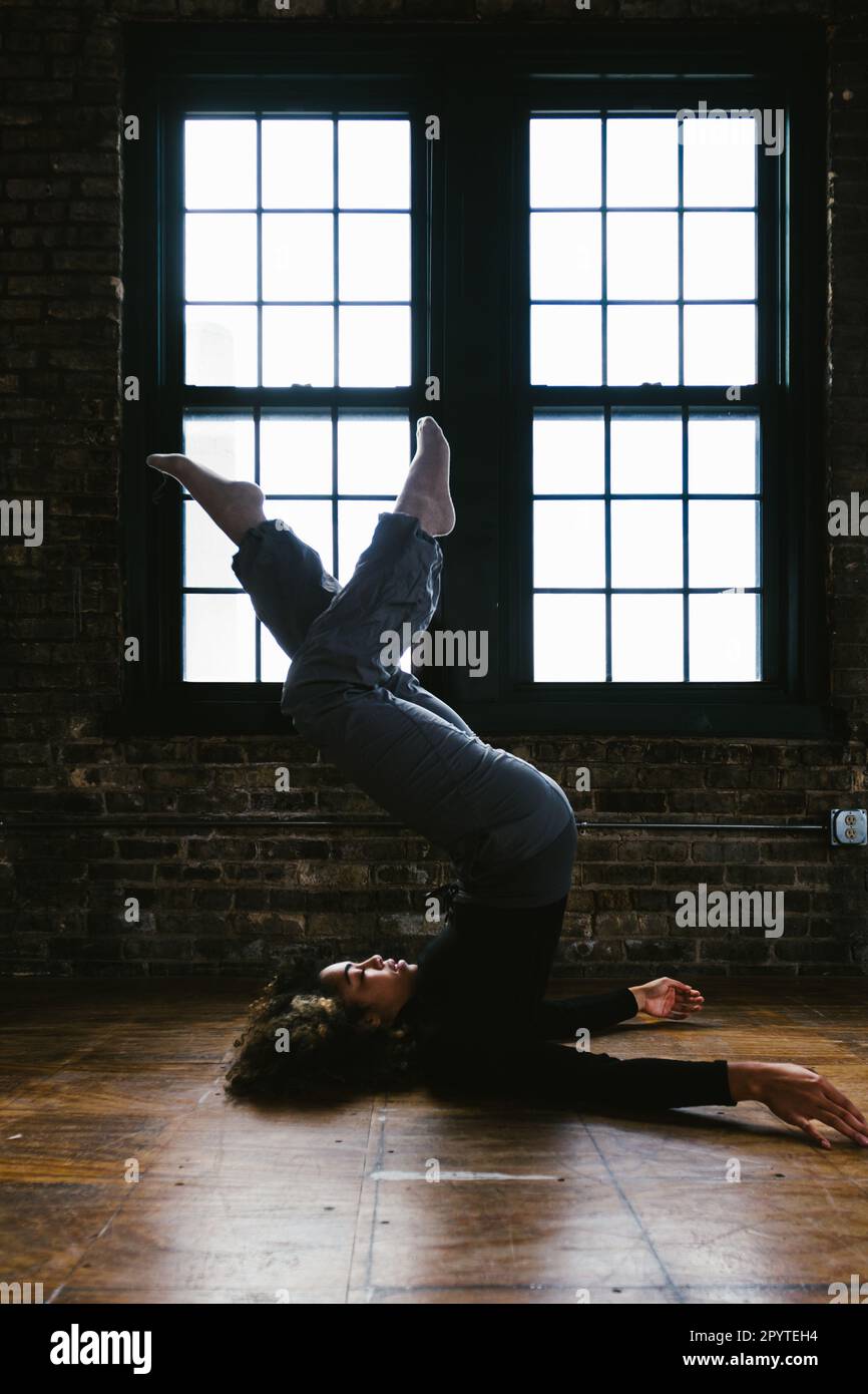 Profile shoulder stand by black female dancer back light from window ...