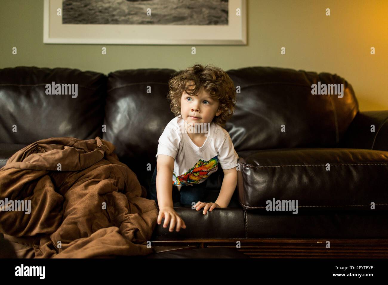 Young boy crawling on edge of couch Stock Photo - Alamy