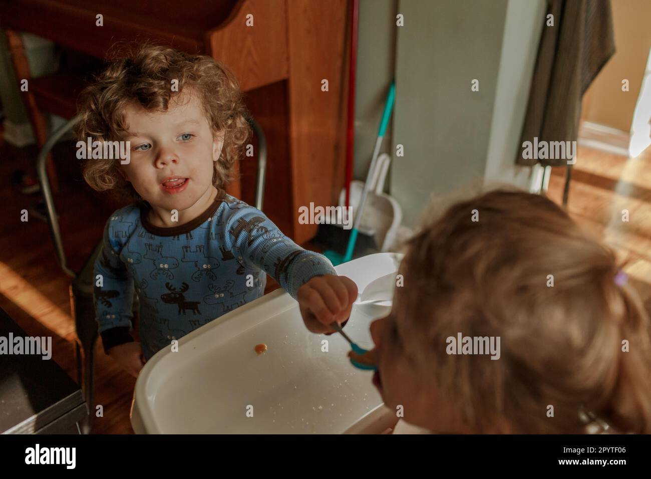 Toddler feeding younger sibling food Stock Photo - Alamy