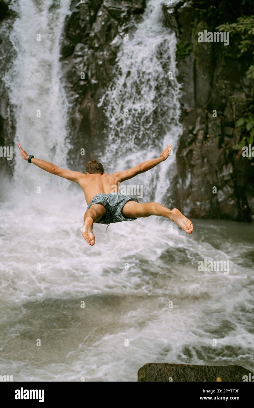 A man jumps from a waterfall. Bali Stock Photo - Alamy