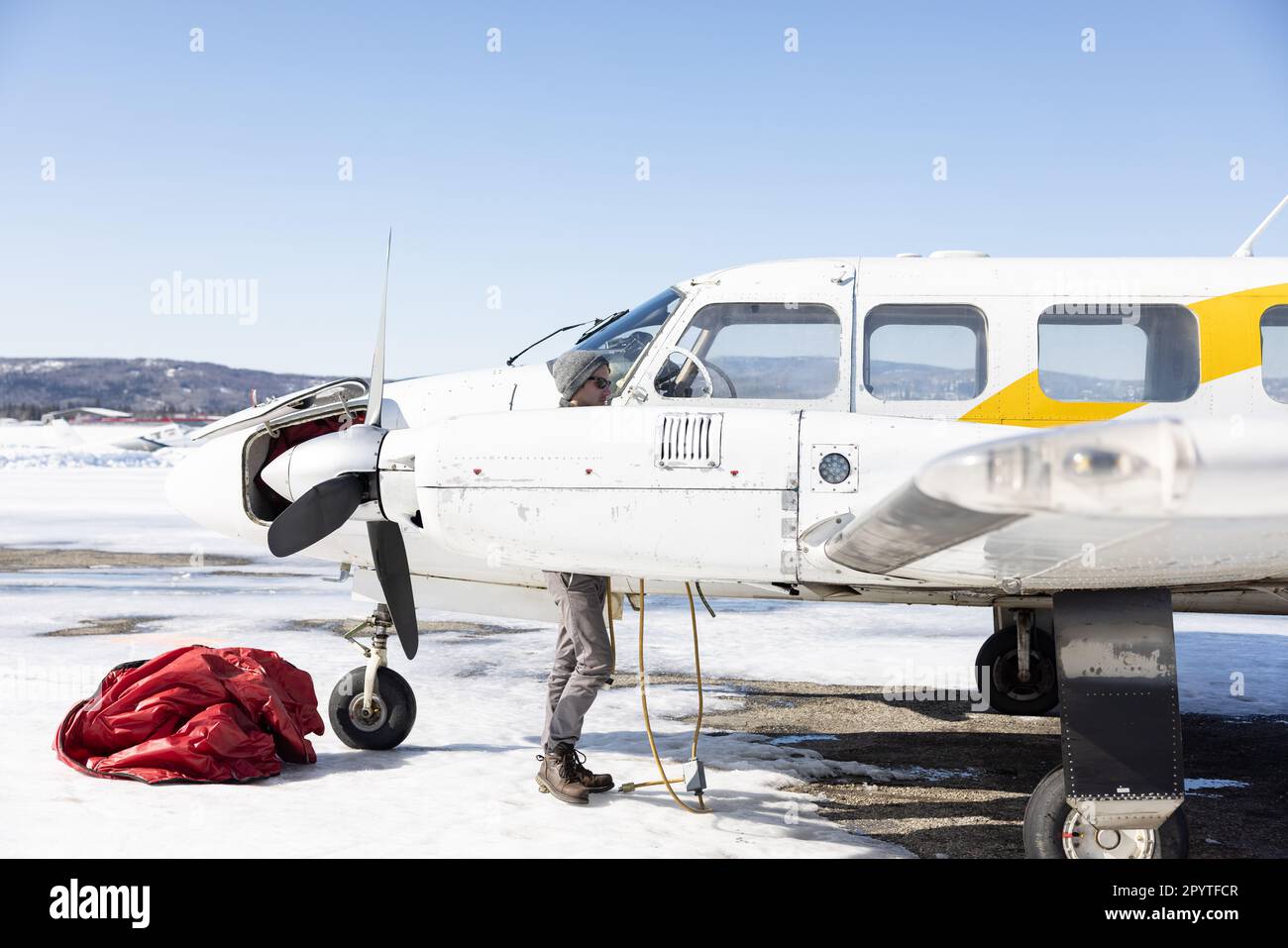 Pilot doing maintenance on small aircraft on runway in Alaska Stock ...