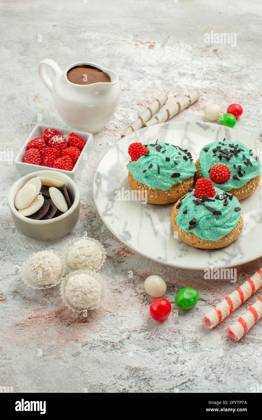 front view colorful candies with cream cakes on white background ...