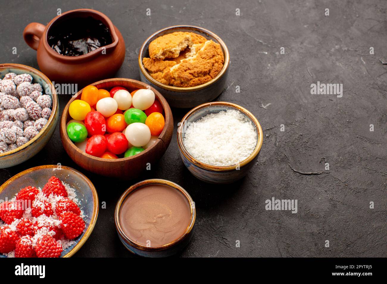 front view different colorful candies with confitures on dark desk ...