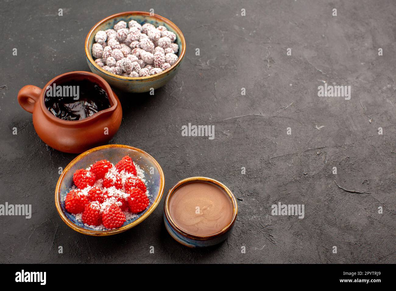 front view different candies with chocolate syrup on dark grey ...