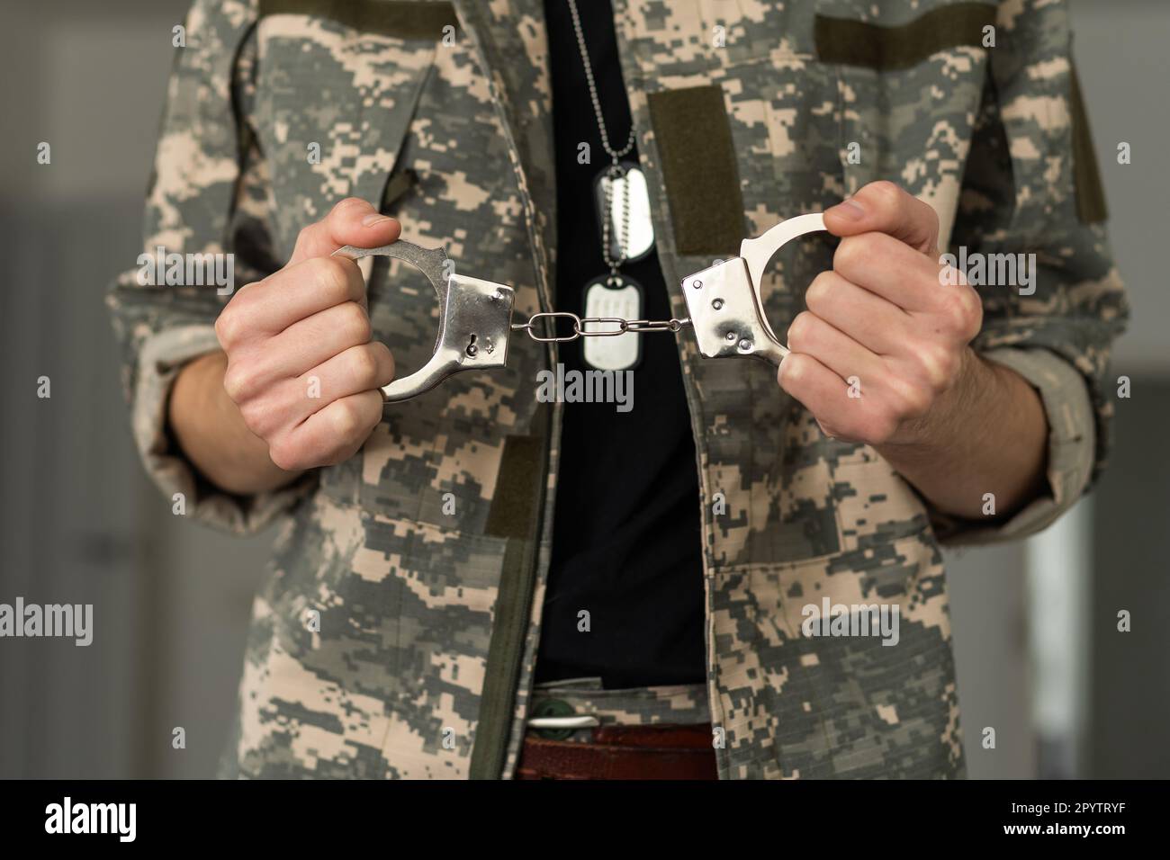 A handcuffed soldier behind the bars against a black background ...