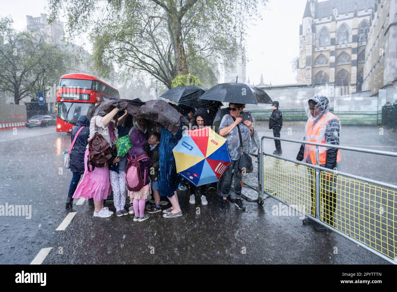 London UK. 5 May 2023. Pedestrians and royal fans take cover as they ...