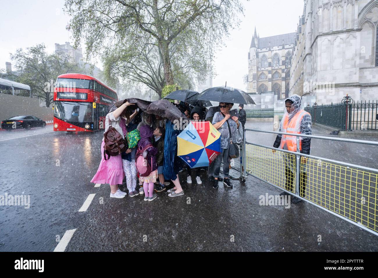 London UK. 5 May 2023. Pedestrians and royal fans take cover as they ...