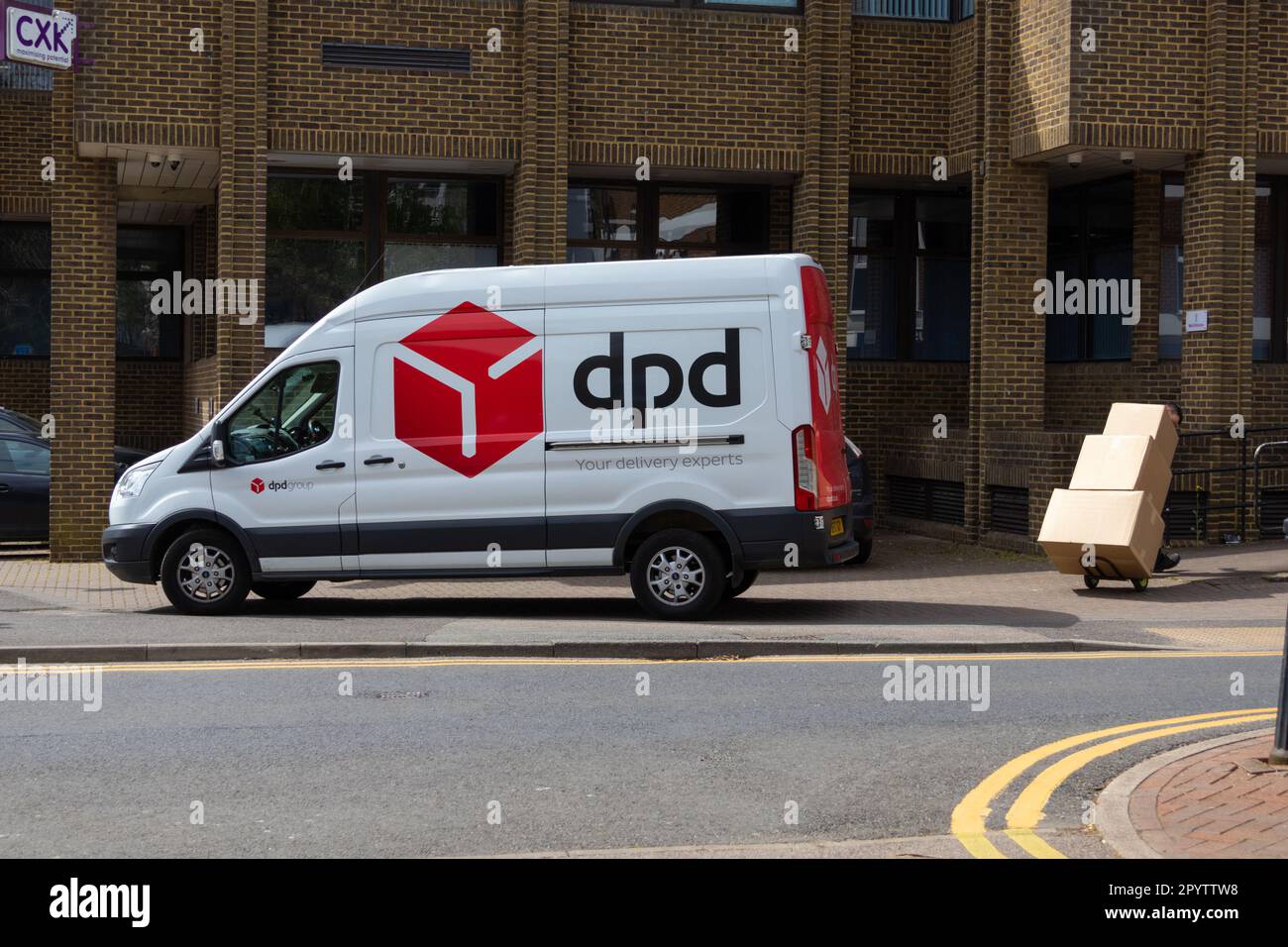 DPD delivery van parked on pavement with driver carrying boxes, ashford ...
