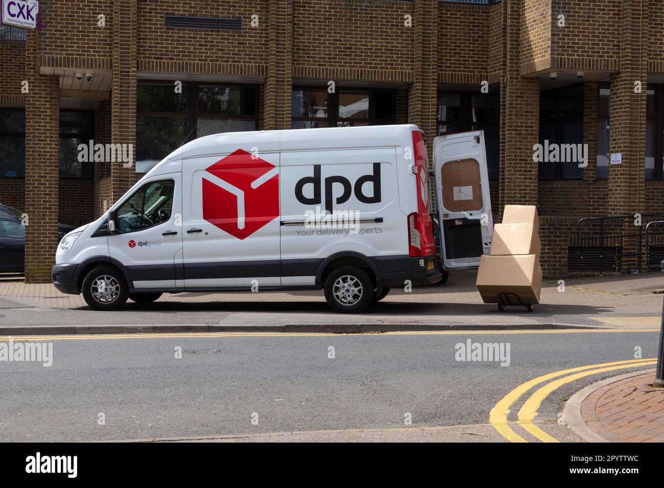 DPD delivery van parked on pavement with driver carrying boxes, ashford ...