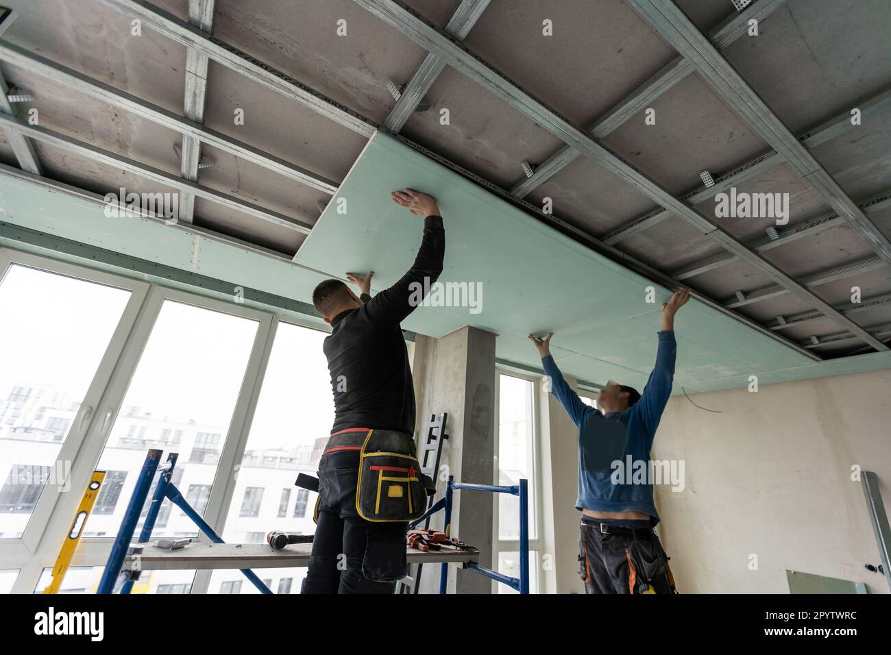 Workers fitting panel into frame of ceiling Stock Photo - Alamy