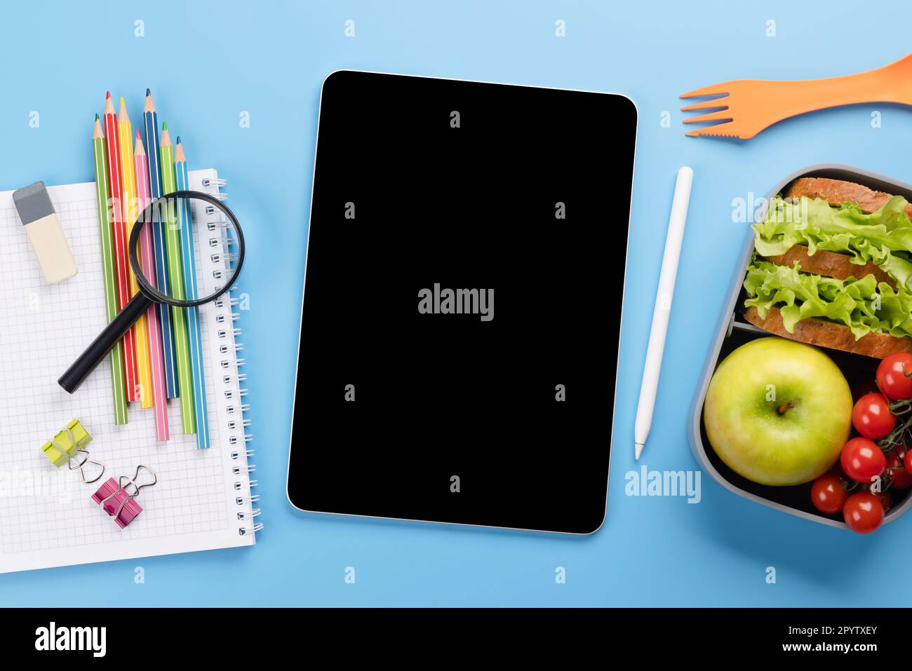 Tablet with blank screen, school supplies, stationery, and lunch box on ...