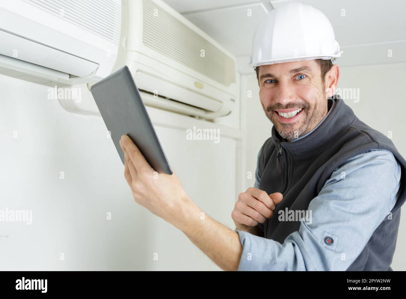technician with tablet by air conditioning unit Stock Photo - Alamy