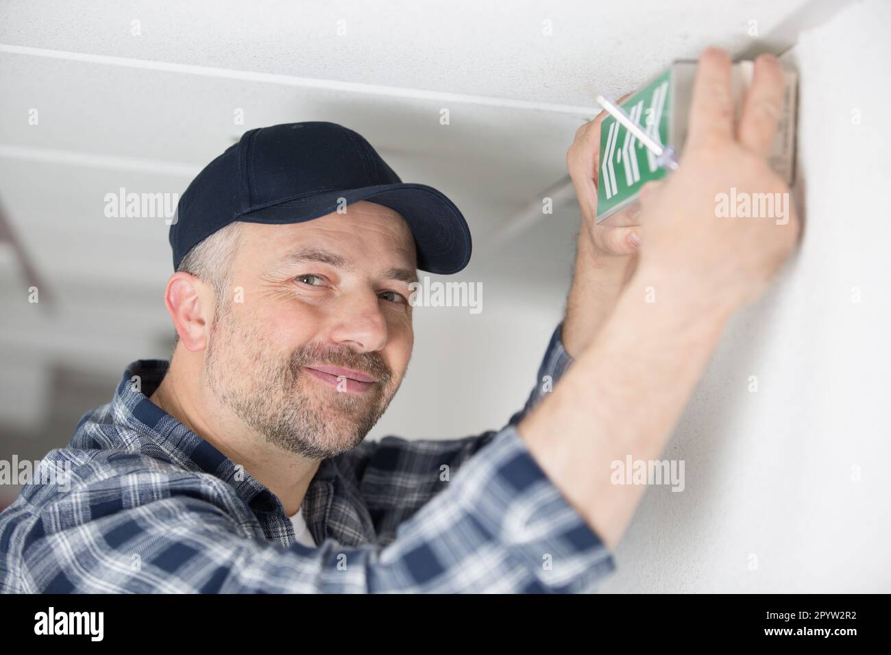 a male worker and emergency exit sign Stock Photo - Alamy