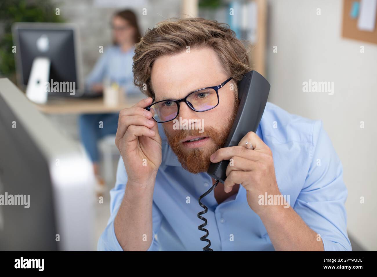 serious concentrated fashionable male office worker calls to colleague ...