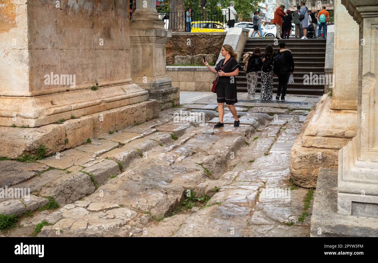 A female tourist stops to take a selfie on the deeply rutted pavement ...