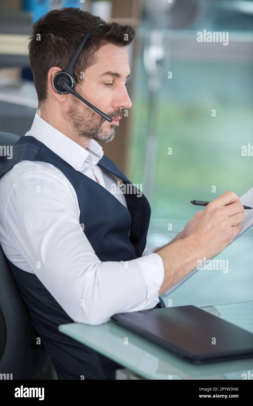 smartly dressed man wearing headset making notes on clipboard Stock ...