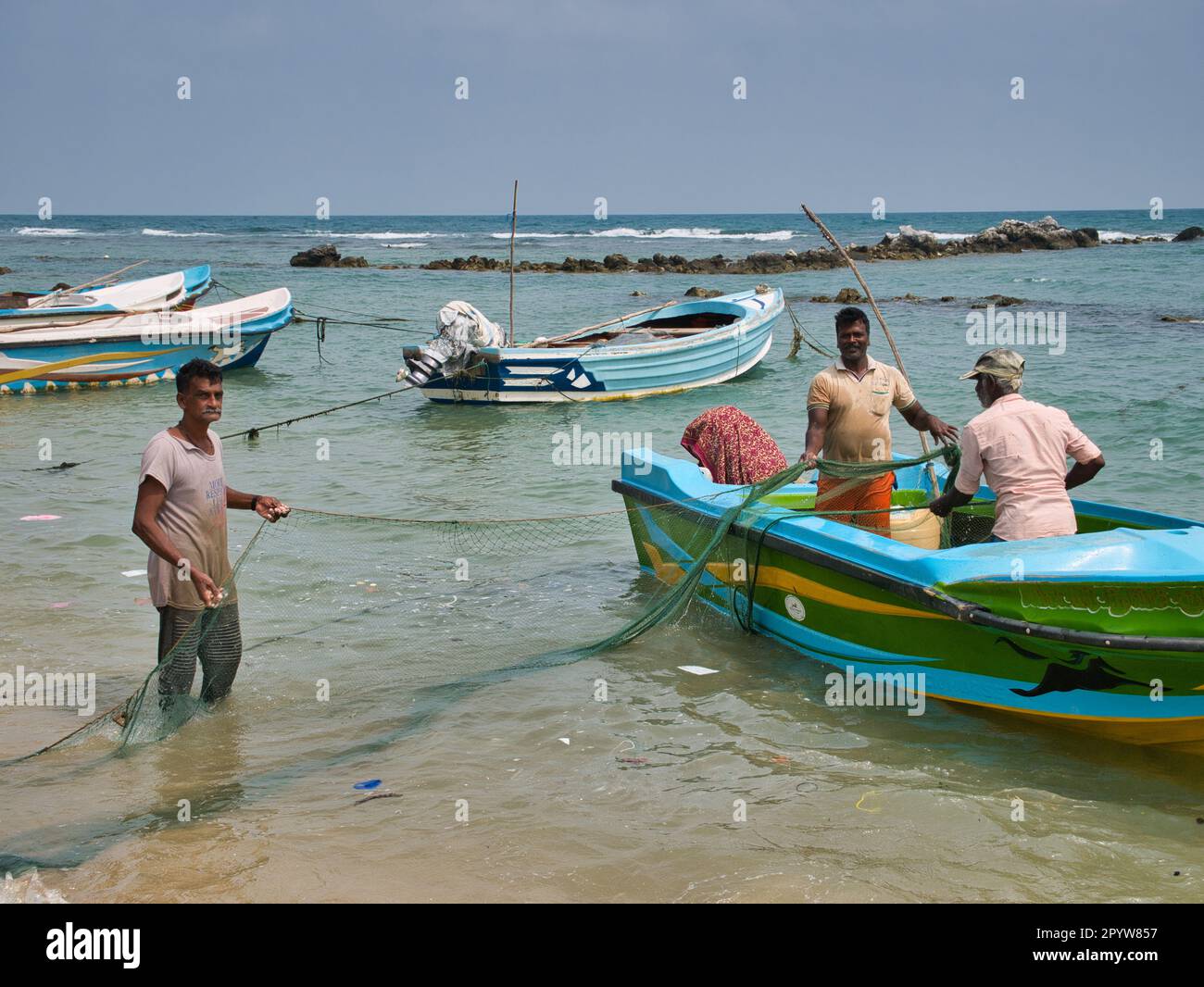 Three fishermen prepare an load fishing nets before a fishing trip ...