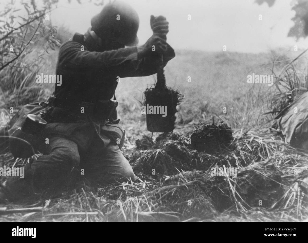 A German infantryman digs in with his folding spade during the ...