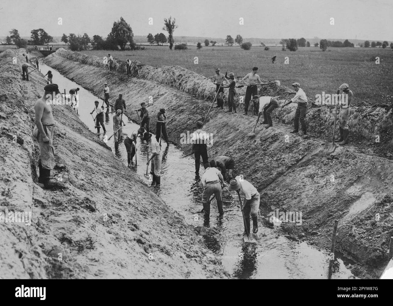 Members of the Voluntary Labor Service building a drainage ditch to ...