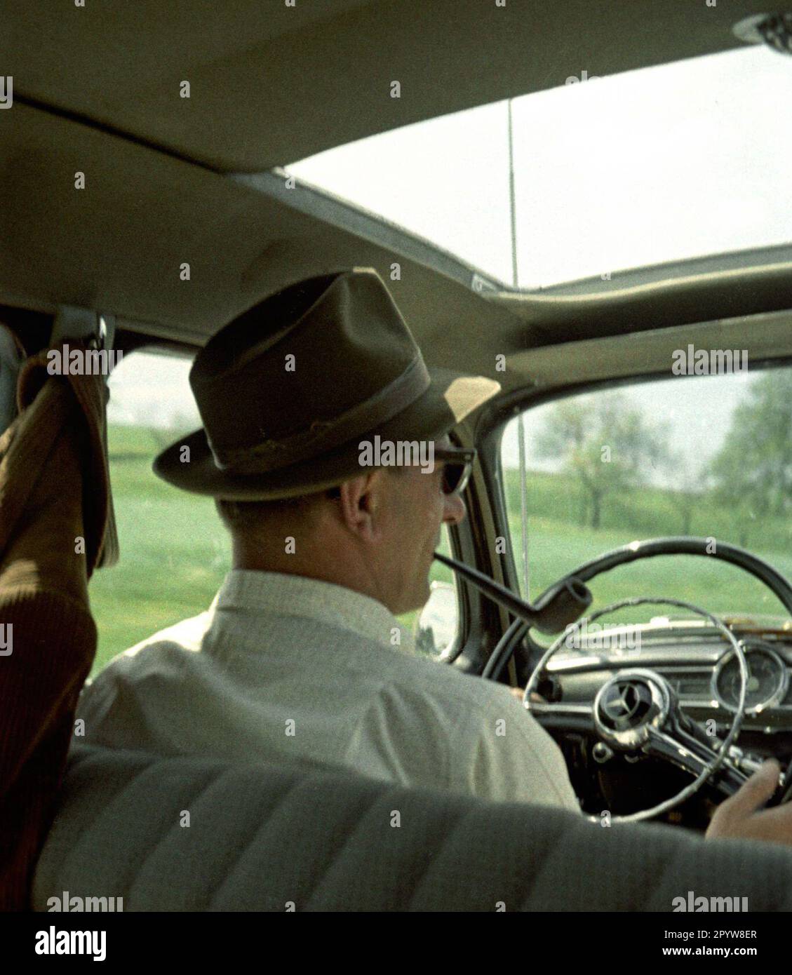 A man is sitting in his car smoking a pipe. [automated translation ...