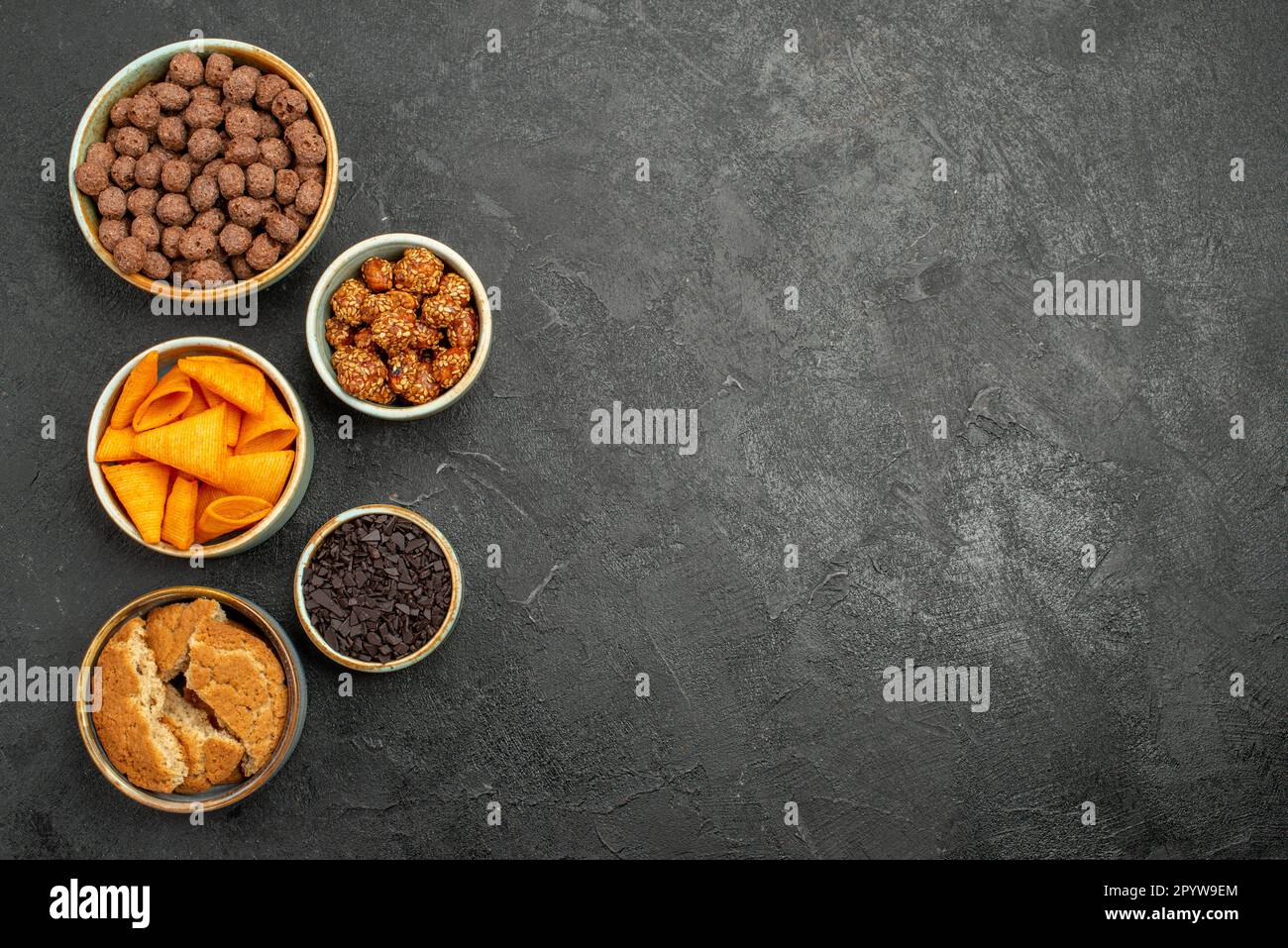 top view nuts and chips inside little pots on dark-grey desk color ...