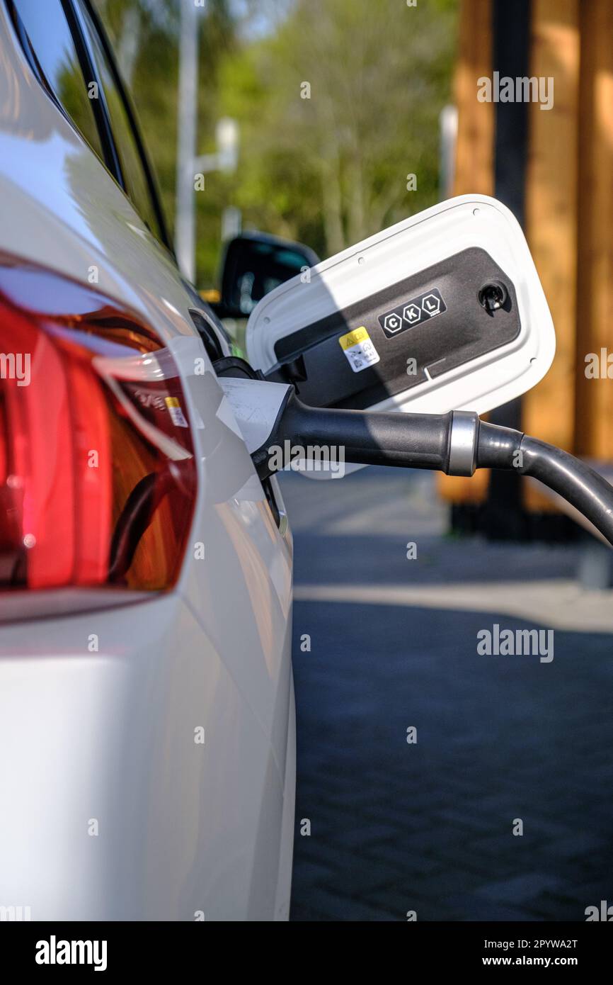 A close-up shot of an electric car charging at a recharging station ...