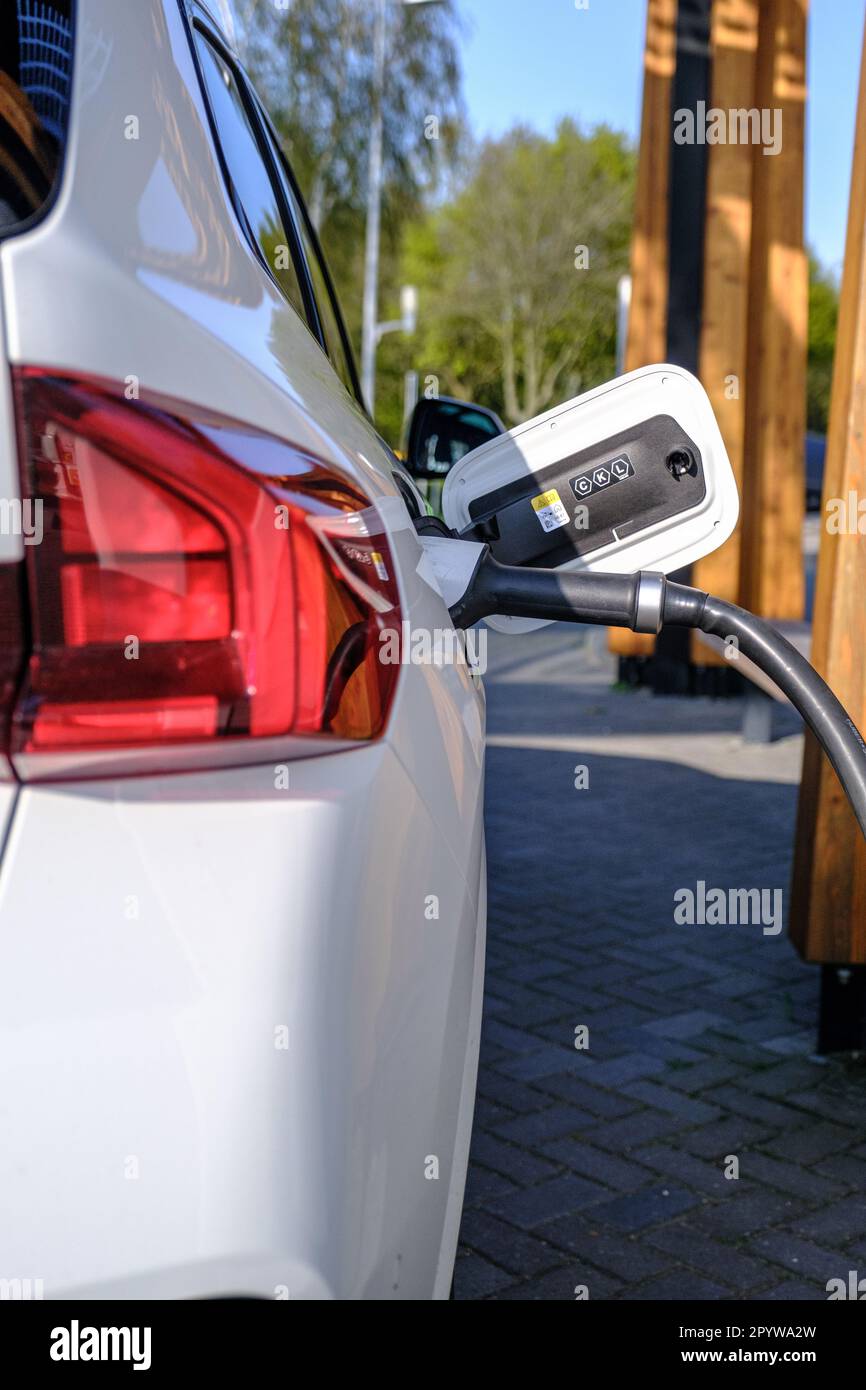 A close-up shot of an electric car charging at a recharging station ...