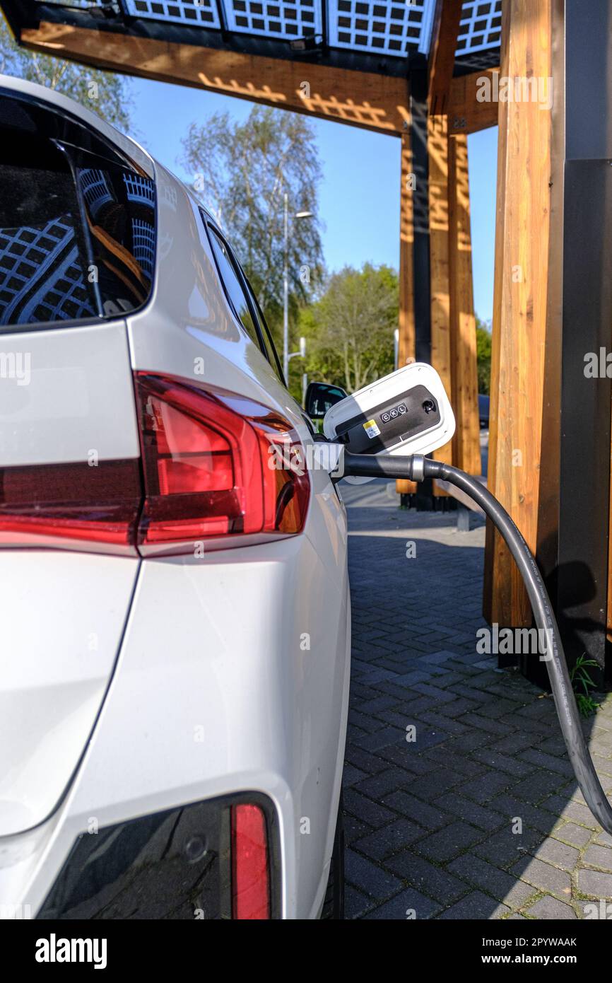 A close-up shot of an electric car charging at a recharging station ...