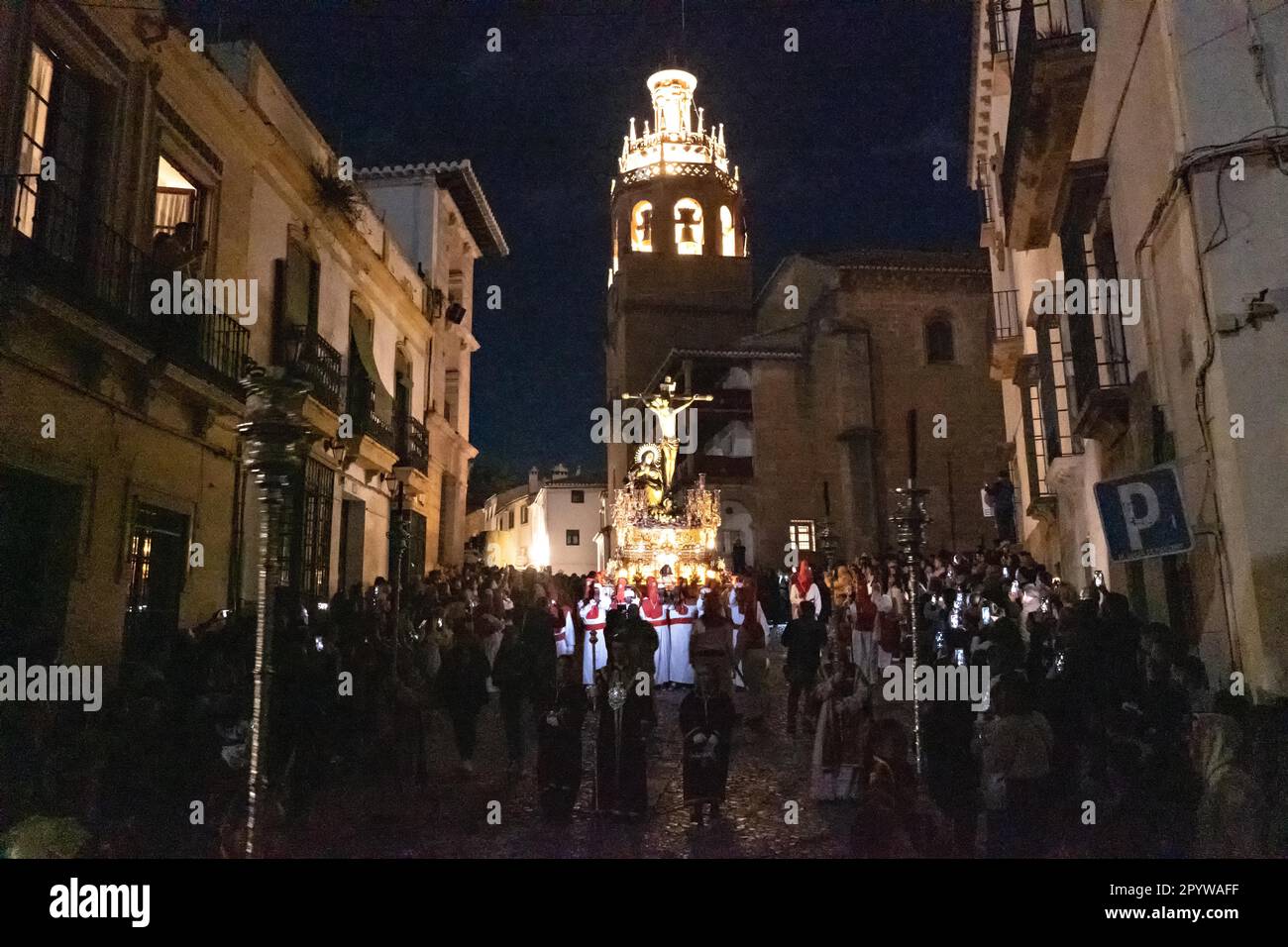 Nazarenos wearing red cone shaped hoods carry a massive platform of the ...