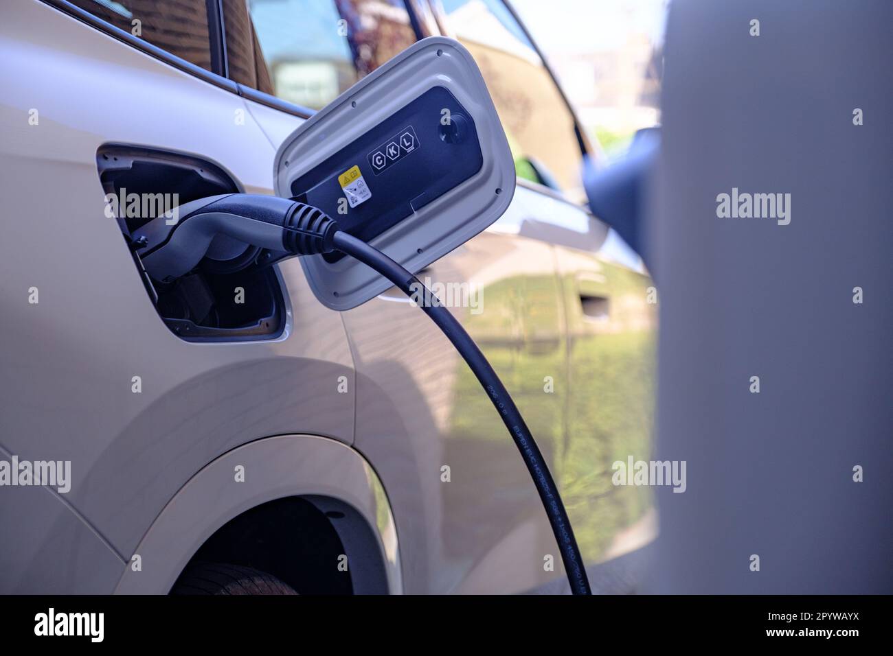 Close up of a white electric car being charged by a charging station ...