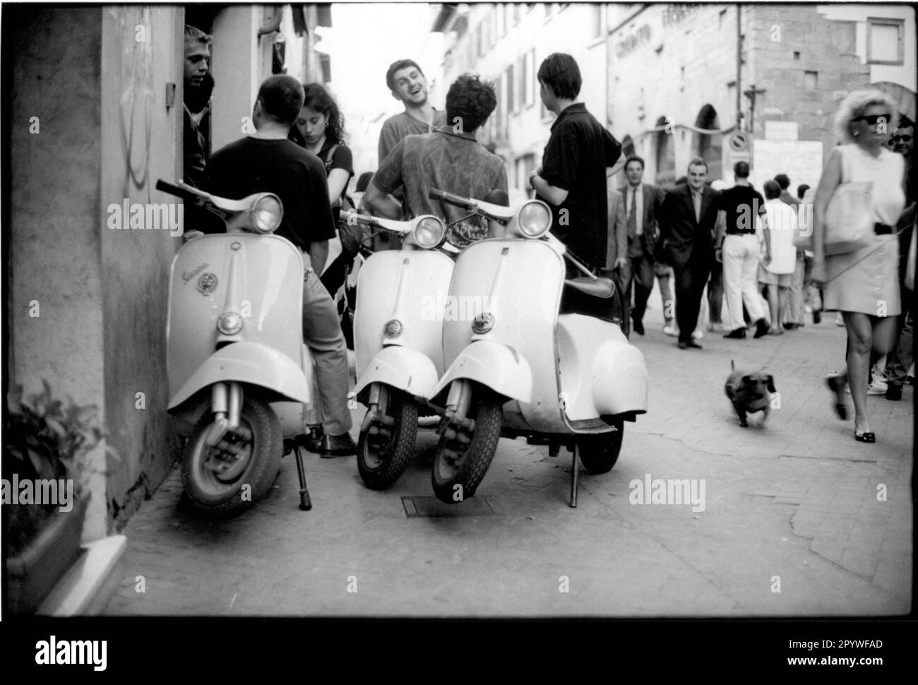 Italy, Arezzo. Vespa in series. Young people stand next to their Vespas ...