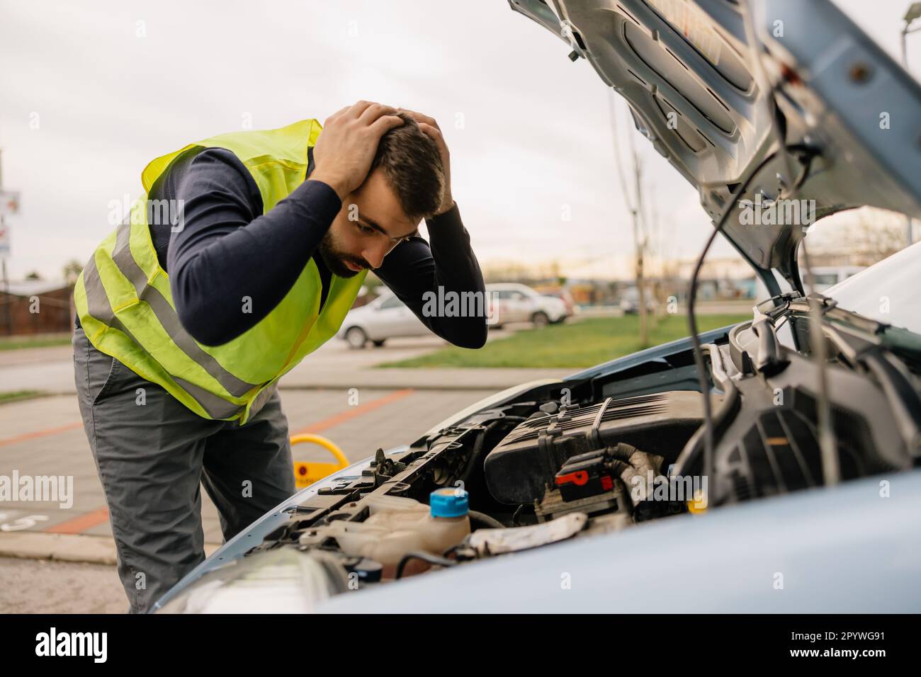 A Man is standing next to his car formally dressed and looking worried ...